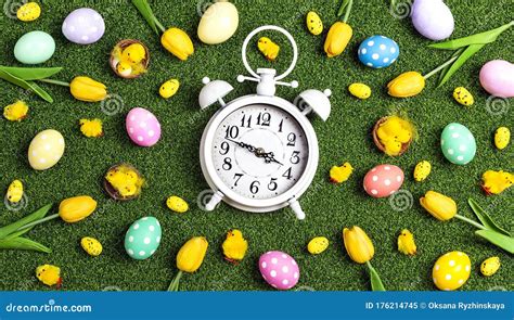 Easter Alarm Clock With Colorful Eggs And Tulips On A Green Grass