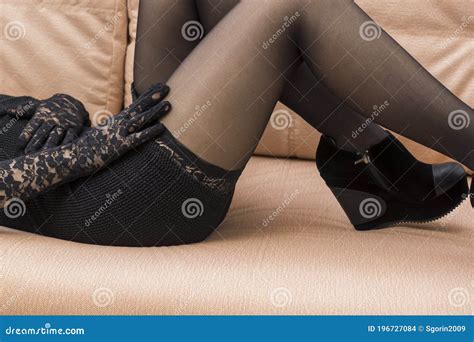 Legs Of Girl In Black Stockings Gloves And Short Black Dress On Sofa