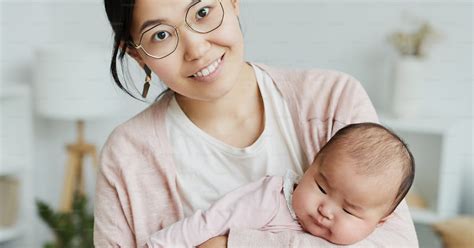 아시아의 젊은 여성이 방에 서서 어린 아이를 안고 카메라에 미소를 짓고 있다 사진 Unsplash의 실내 이미지