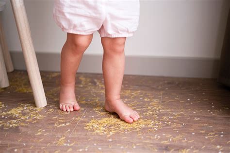 곡물 견과류 파스타 및 쌀로 놀고 난 후 지저분한 바닥에 서있는 유아 소녀 다리 감각 조기 발달 아기 어린이를위한 교육 어린이 더러운 방 개념 바닥재에 대한 스톡 사진 및