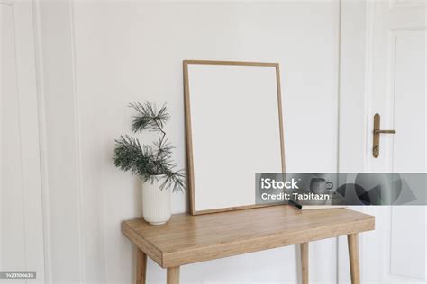 크리스마스 스칸디나비아 인테리어 빈 수직 나무 그림 프레임 모형 꽃병에있는 소나무 가지 커피 한 잔 및 테이블 책상에있는 오래된