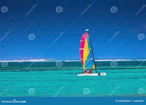 People On A Color Catamaran Sailboat Or Winsurf Sailing In Calm
