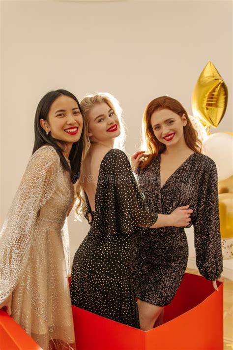 Three Young Interracial Girls In Trendy Dresses Are Standing Indoors