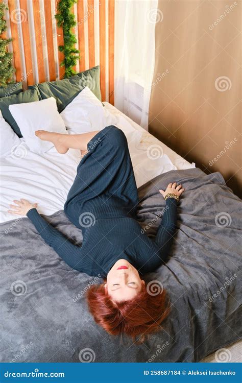 Fifty Years Old Red Haired Woman Lying Upside Down In Bedroom Stock