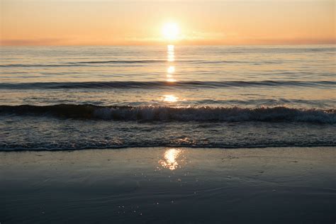 해변의 물 위로 해가 지고 있습니다 사진 Unsplash의 무료 헤이그 이미지
