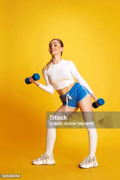 Full Lenght Image Of Young Woman In Training Pumping Up Muscles Of