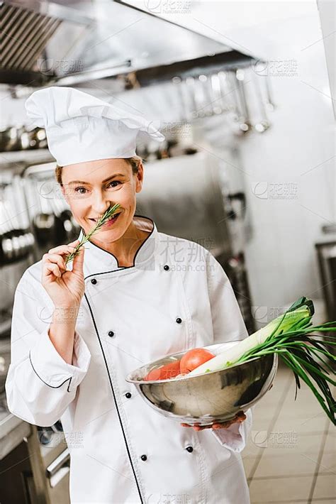 美丽微笑的女厨师制服拿着迷迭香和碗蔬菜在餐厅厨房素材 花瓣网