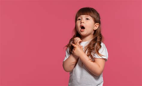 분홍색 스튜디오 배경을 배경으로 포즈를 취한 흰색 티셔츠를 입은 작은 갈색 머리 소녀의 클로즈업 초상화 진지한 감정 개념 T