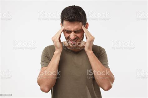 무기력 한 얼굴 표정으로 통증을 완화 하기 위해 눈을 감고 사원 손가락을 누르면 회색 배경에서 심한 두통 고통에 고립 된 젊은