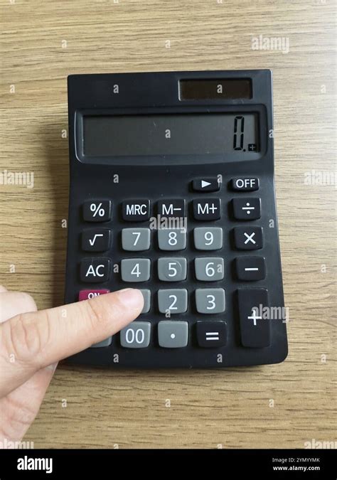 A Hand Pressing A Button On A Black Calculator With A Digital Display Showing The Number 0 Stock