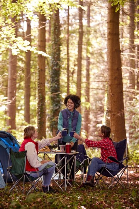 Group Of Female Friends On Camping Holiday In Forest Drinking Coffee
