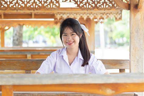 나무 의자에 앉아 흰색 학교 유니폼을 입은 태국 여학생 나무 테이블에 미소 귀여운 학생 18 19세에 대한 스톡 사진 및 기타