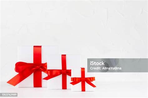 흰색 선물 상자는 빨간색 새틴 리본과 흰색 테이블에 활과 부드러운 빛 벽에 활 복사 공간을 다른 크기 3가지 개체에 대한 스톡 사진 및 기타 이미지 Istock