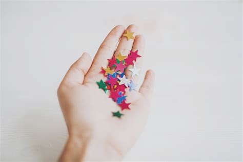 흰색 배경에 화려한 별 색종이 또는 반짝이를 들고 손 세련 된 분위기 이미지입니다 생일 축하 개념입니다 휴일 장식 손에 매직