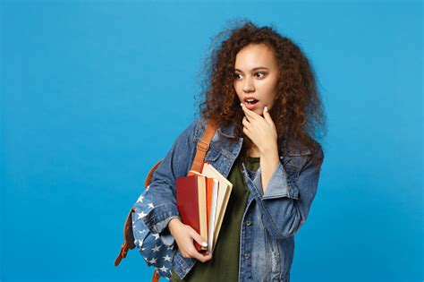 데님 옷에 젊은 슬픈 아프리카계 미국인 소녀 사춘기 학생 배낭은 파란색 배경 스튜디오 초상화에 고립 된 책을 보유 고등학교 대학 대학 개념에서 교육 복사 공간을 모의 합니다