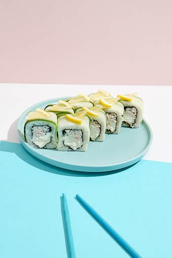 컬러 배경에 게와 신선한 마키 롤 스시 롤 안에 게와 치즈 오이와 레몬 외부 최소한의 스타일로 녹색 마키 초밥 일본어 메뉴 컨셉