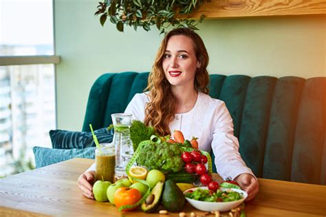 배경에 녹색 사무실에서 다른 건강 식품 재료와 함께 앉아 다이어트 계획에 작업 하는 테이프 측정 의료 제복을 입은 여성 영양사 체중 감량과 올바른 영양 개념 개념에 대한