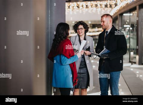 Three Colleagues Engage In A Relaxed Business Discussion Exchanging