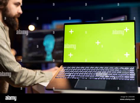 Focus On Green Screen Laptop Used By Engineer Wearing Eeg Headset In Blurry Background To Upload