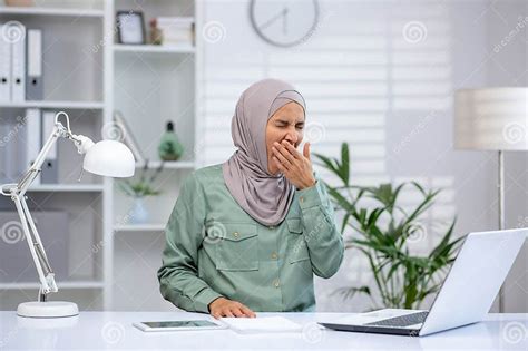 Tired Businesswoman Yawning While Working On Laptop In Modern Office Setting Stock Image Image