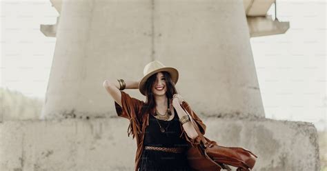 세련된 힙스터 여자는 강 돌 근처에 바람이 부는 머리를 가진 모자를 쓰고 재미있고 웃고 있습니다 집시 룩의 보헤미안 여행자 소녀 여름 여행 대기 순간 텍스트 공간