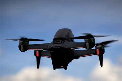 뒤에서 검은 Dji Fpv 무인 항공기 프로펠러와 빨간색 Led 조명어두운 레이싱 드론 배경에 흰색 구름과 푸른 하늘 후면 보기
