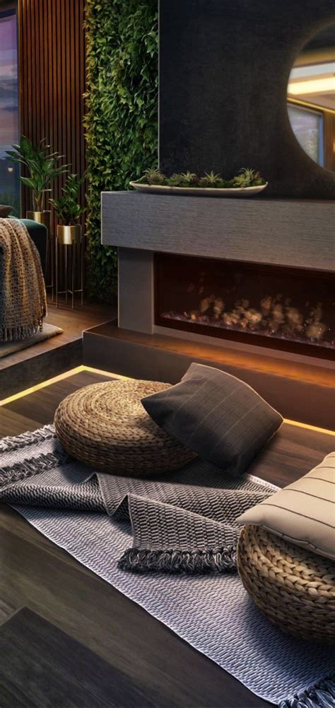A Living Room With A Fire Place In The Center And Pillows On The Floor