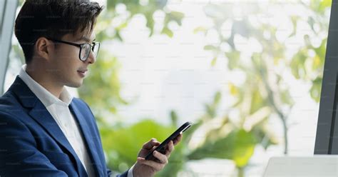 크리에이티브 에이전시 스마트 안경 아시아 남성 공식 천 대화 스마트폰 프리랜서 공동 작업 공간에서 노트북으로 작업 사무실 공간 흐릿한 사무실 배경으로 신선함 사진