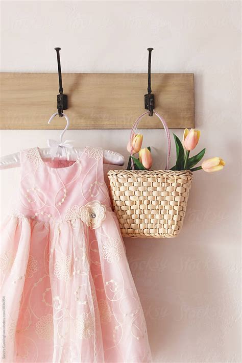 Little Pink Dress With Straw Purse Hanging On Hooks By Stocksy