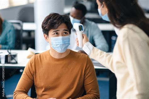 Teacher With Contactless Thermometer Measuring Temperature Of Asian Student Stock Photo Adobe