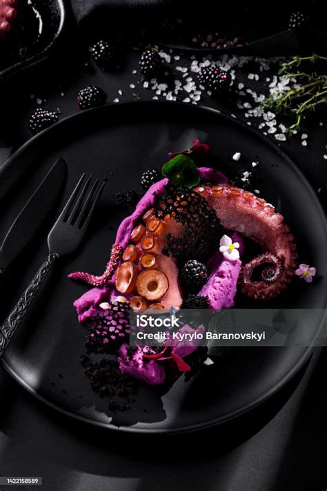 핑크 셔벗 칠면조 잎 블랙 베리 레이스 소스 꽃잎 및 칼 붙이를 블랙 베리 소금 및 백리향이있는 테이블 위의 접시에 곁들인 낙지