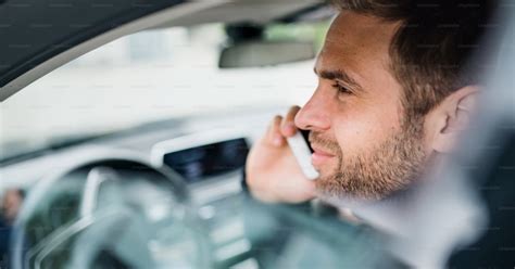 스마트폰을 들고 차를 타고 전화를 걸고 있는 젊은 사업가의 클로즈업 사진 Unsplash의 회색 색상 이미지