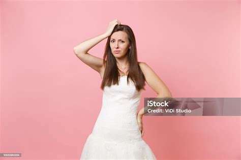 하얀 웨딩 드레스 스탠드에 우려 의아해 신부 여자의 초상화 문제 유지를 핑크 파스텔 배경에 고립 된 머리에 손이 있다 결혼식 축