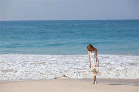 Conceito de moda de férias de verão bronzeando mulher usando chapéu de sol na praia em uma areia