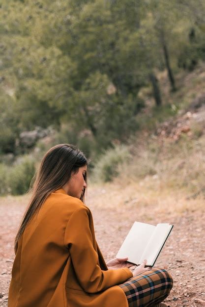 Jeune Femme Assise Sur Le Sol En Lisant Le Livre Photo Gratuite