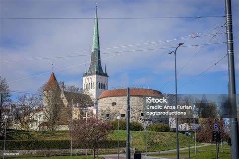 에스토니아 탈린의 중세 구시가지에는 높은 첨탑이 있는 상징적인 성 올라프 교회와 구름이 흩어져 있는 푸른 하늘 아래 둥근 돌 팻 마가렛 타워가 있습니다 0명에 대한 스톡