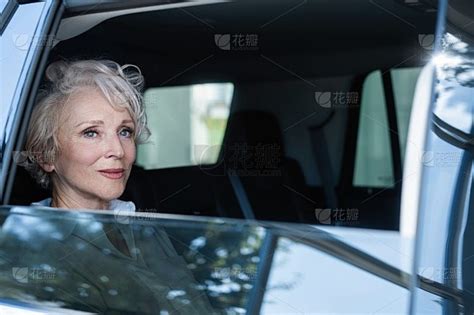 女企业家坐豪华轿车去上班，坐在后座上。
