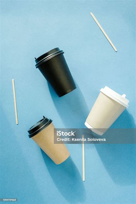 설탕을 혼합하기위한 커피와 나무 막대기를위한 세 가지 색종이 컵은 파란색 배경에 놓여 있습니다 하드 그림자커피 컵 테이크 아웃 음료 개념 디자인용 템플릿입니다 0명에 대한