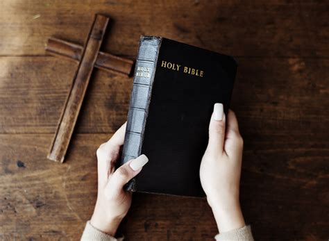 Hands Holding Holy Bible Next To Wooden Cross The Bible Source Blog