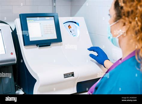 Mature Nurse Analyzing Blood Sample Through Machinery At Laboratory