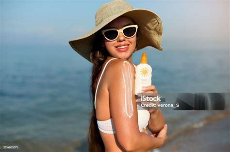 선탠 로션 또는 보습 자외선 차단제를 들고 있는 여성의 초상화 아름 다운 여자가 검게 그을린 어깨에 선크림을 바르고 있습니다 자외선 차단제 피부 및 바디 케어 개념 피부에