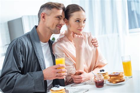 잘생긴 남자 오렌지 주스를 아침에 아침 식사 하는 동안 여자를 포옹 2명에 대한 스톡 사진 및 기타 이미지 2명 남자
