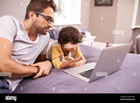 Playing The Guessing Game A Father And Son Using A Laptop While Lying