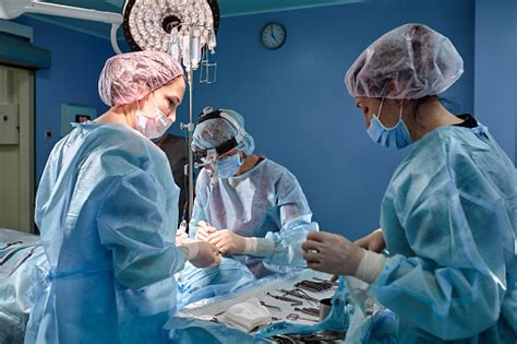 병원 수술실에서 전문 외과 의사와 조수의 국제 팀은 현대적인 수술실에서 작동합니다 전문 의사는 성공적으로 생명을 구한 축하