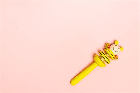 작은 아이를 위한 금속 종소리와 아기 나무로 되는 딸 랑이 복사 공간 분홍색 배경에 노란색 장난감 플랫 레이 스타일 0명에 대한