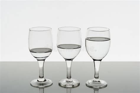 Three Wine Glasses Filled With Water Reflected On The Table Stock Image