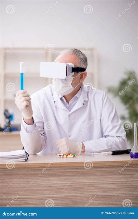 Chemist Wearing Safety Glasses And Coat Sitting In Lab Royalty Free