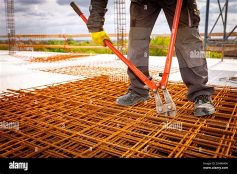 Worker Is Standing On Pile Of Rusty Rectangle Steel Reinforcement For Concrete As Cutting