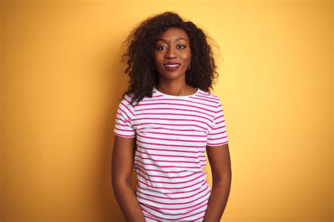 고립 된 노란색 배경 위에 줄무늬 티셔츠를 입은 젊은 아프리카 계 미국인 여성 얼굴에 행복하고 시원한 미소 운이 좋은 사람 T 셔츠에 대한 스톡 사진 및 기타 이미지