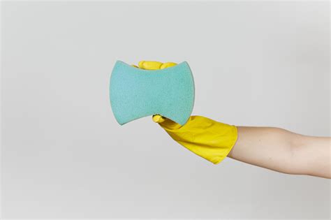 청소에 대 한 노란색 장갑 블루 수평 보유 대형 스폰지에 여성 손의 닫고 흰색 배경에 고립 설거지 청소 공급 개념입니다 광고에